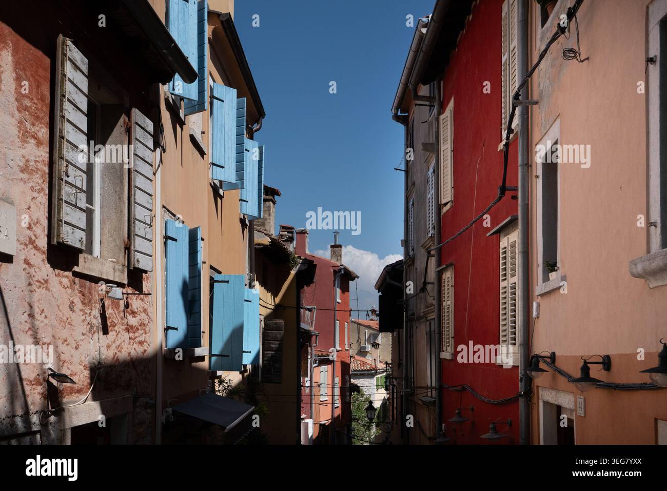 Narrow historic street lined with colorful pastel houses and blue ...