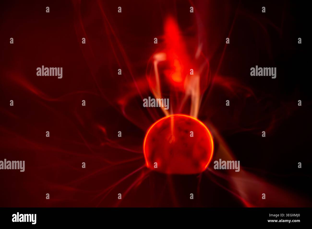 Close-up of a plasma ball globe glowing with red light and energy ...