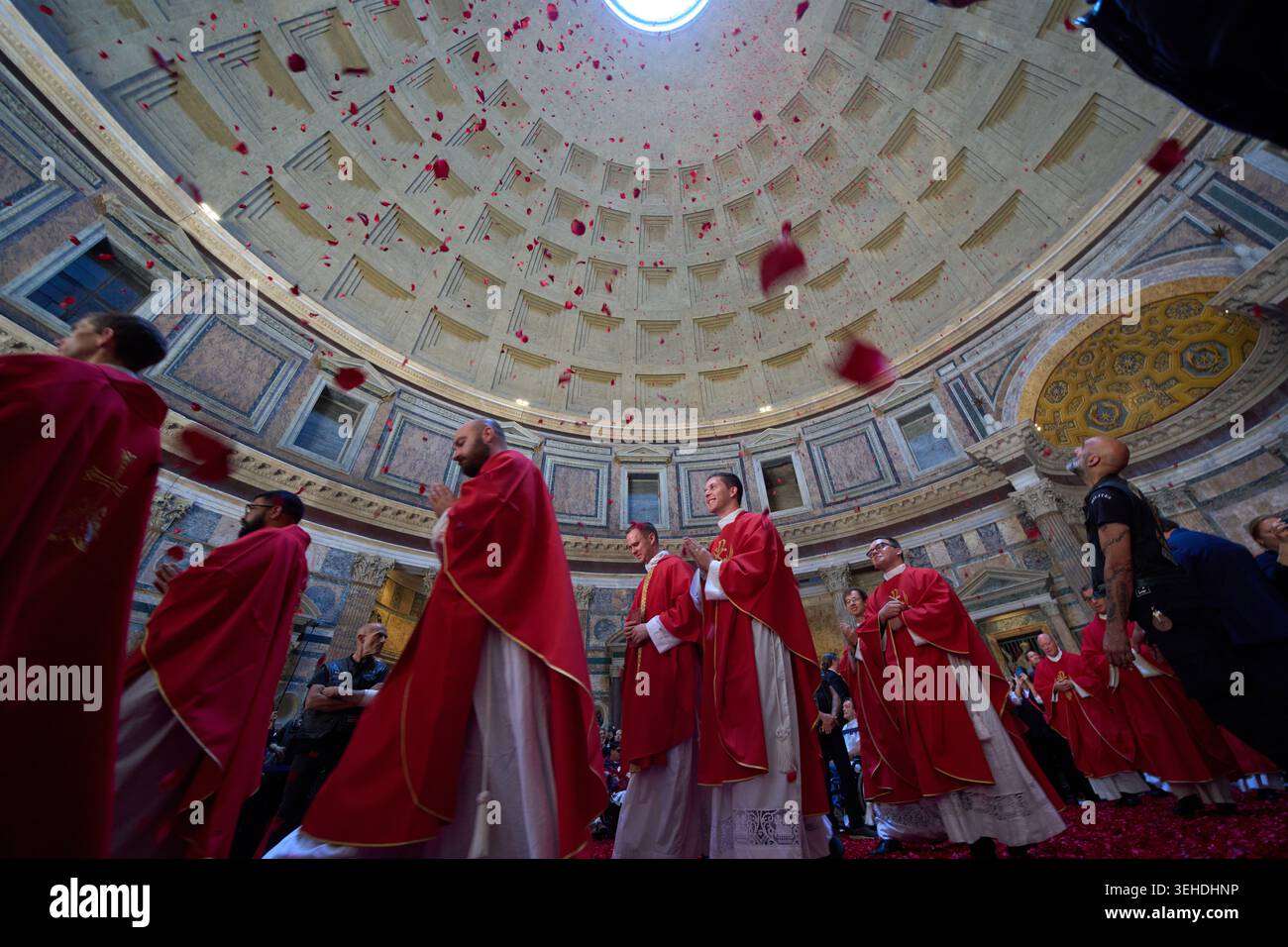 Priests leave in procession as red rose petals are dropped through ...
