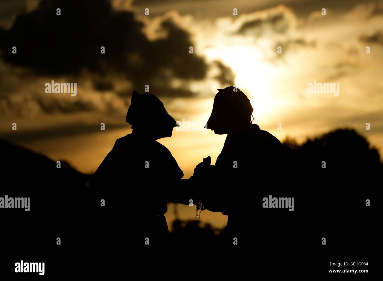 Masked relevers look at each other during sunset at the Cavalhadas, a ...