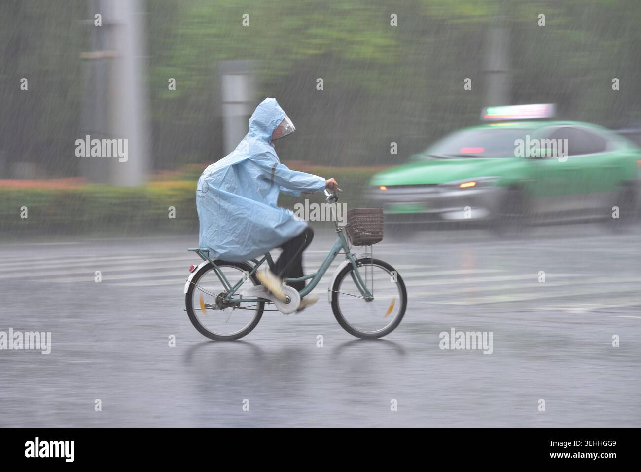 Citizens ride bicycles in the rain on a street in Fuyang, east China's ...