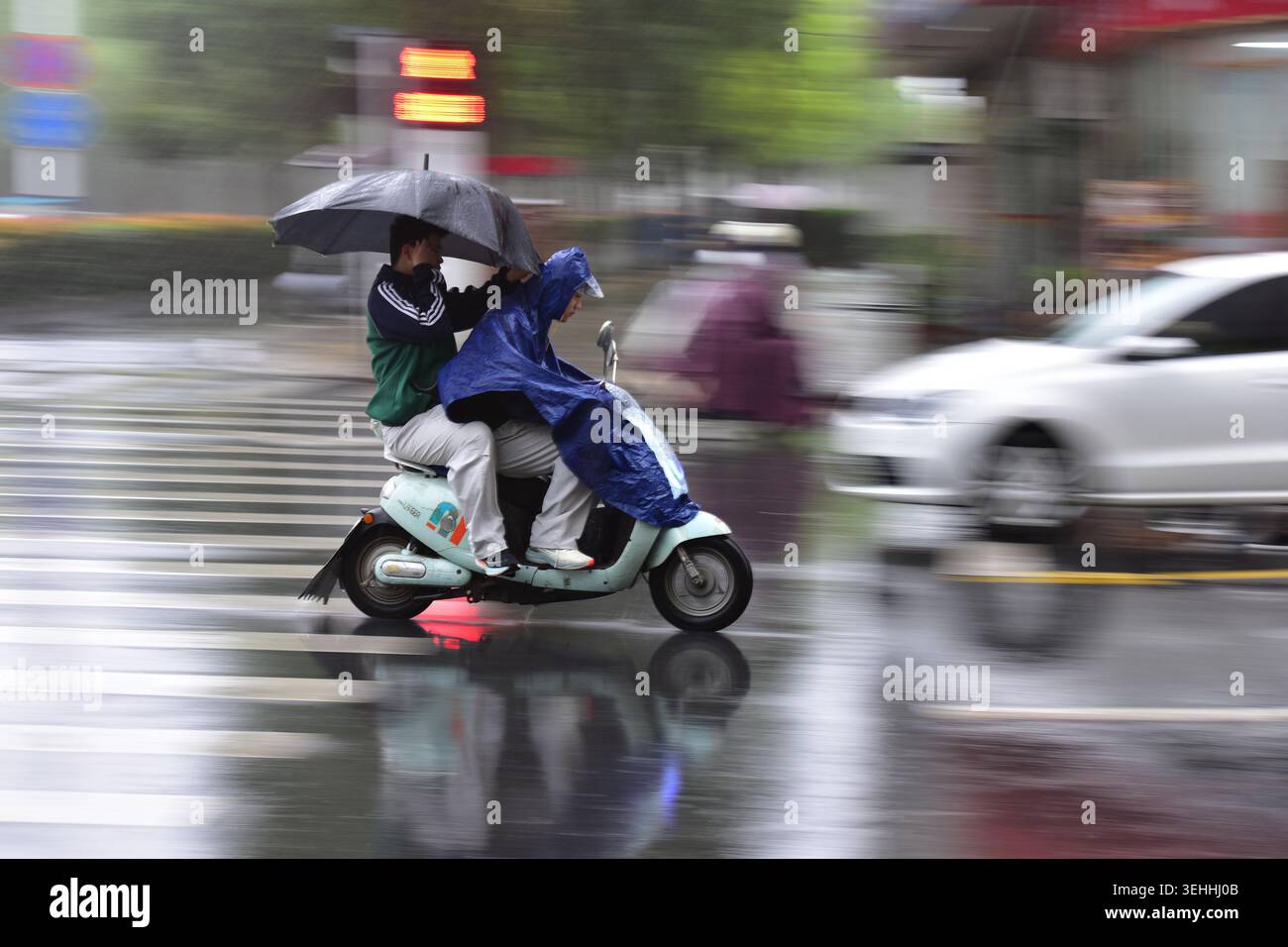 Citizens ride bicycles in the rain on a street in Fuyang, east China's ...