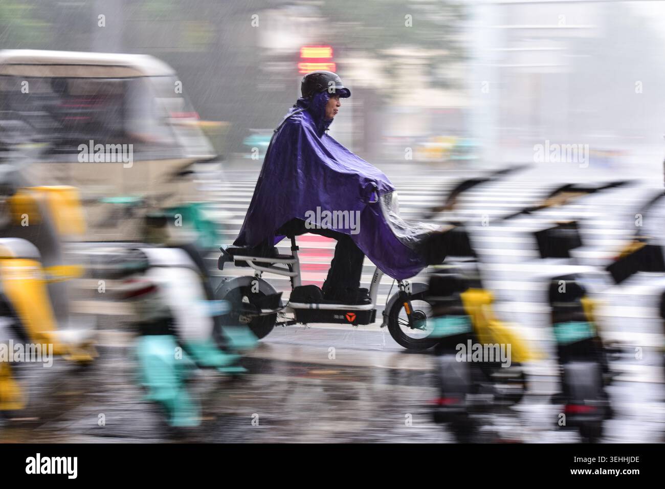 Citizens ride bicycles in the rain on a street in Fuyang, east China's ...