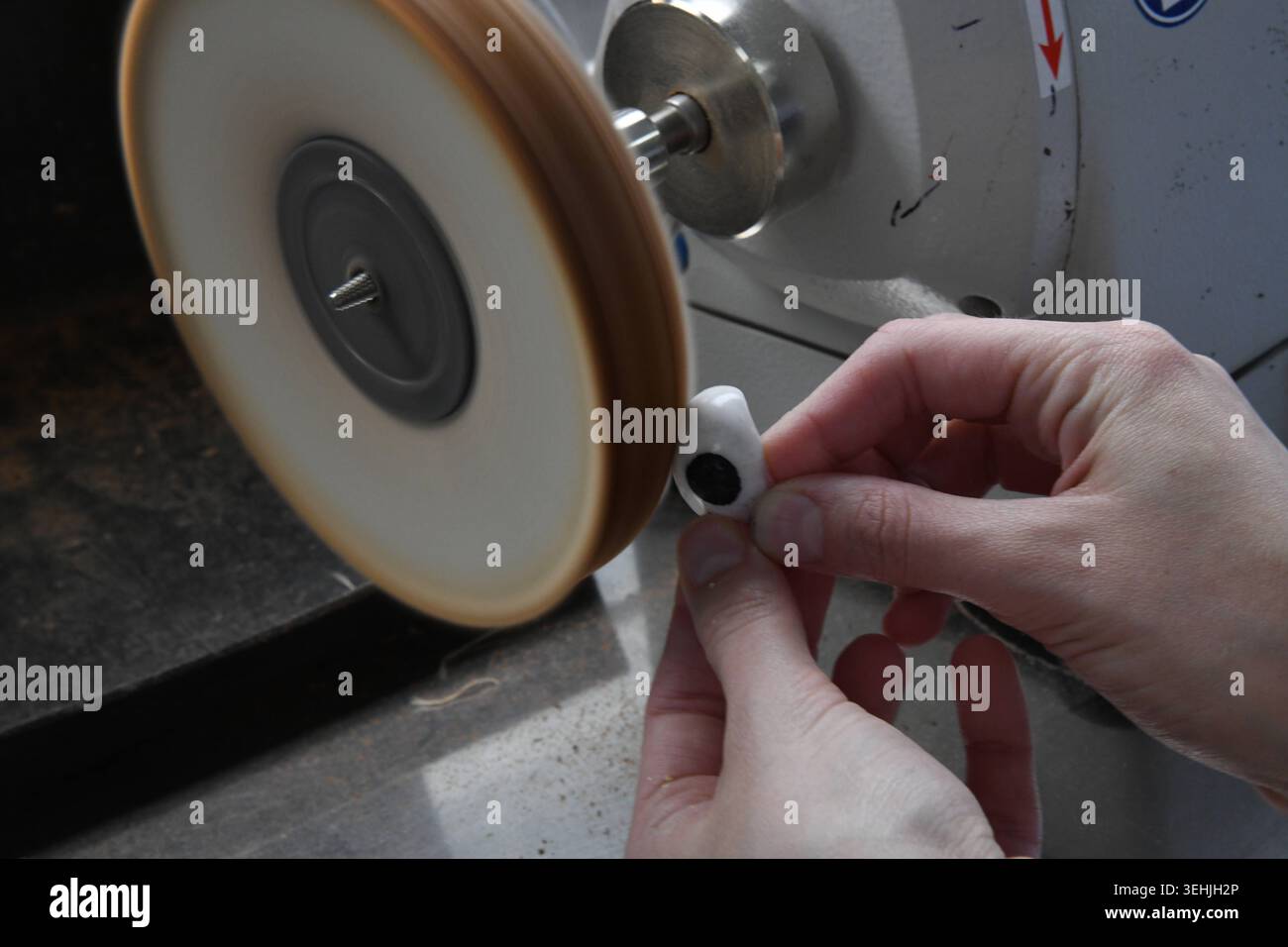 An ophthalmologist holding a white ocular prosthesis against a rotating ...