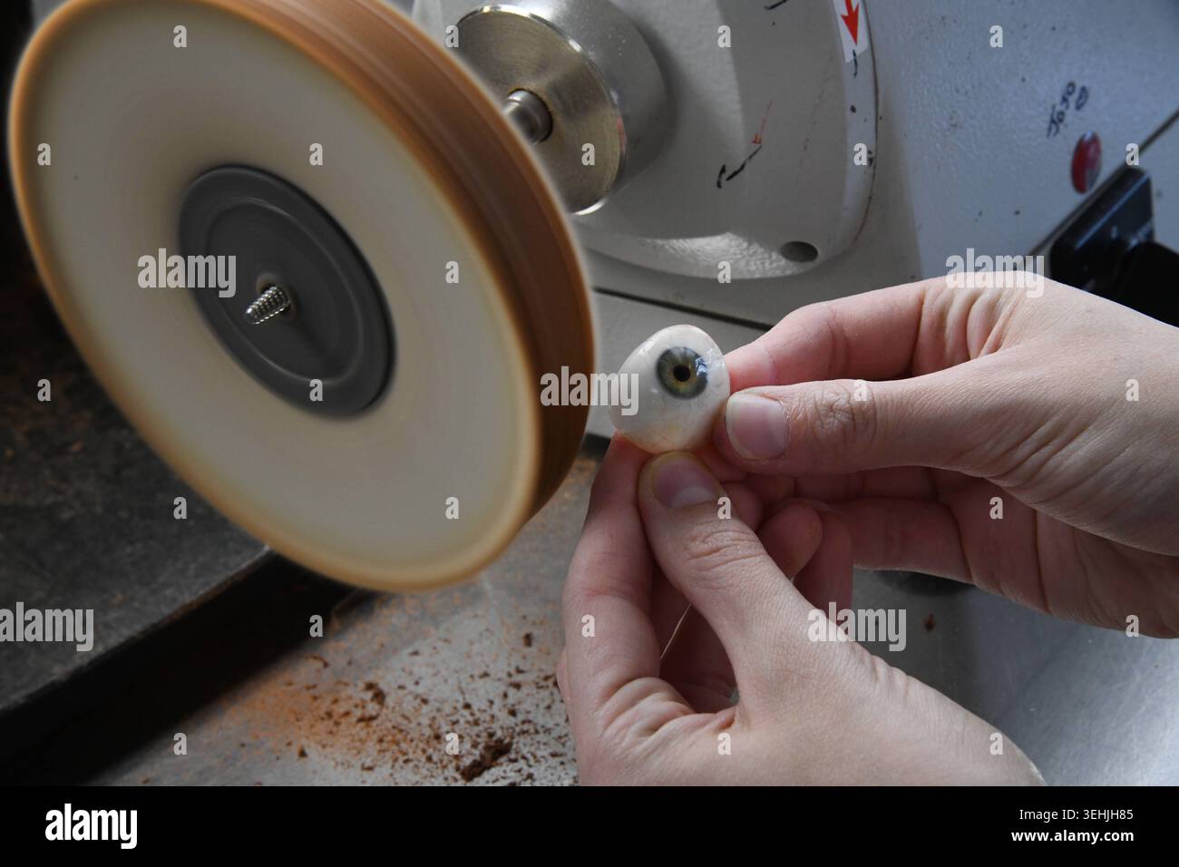 Ocularist holding a custom-made ocular prosthesis against a rotating ...