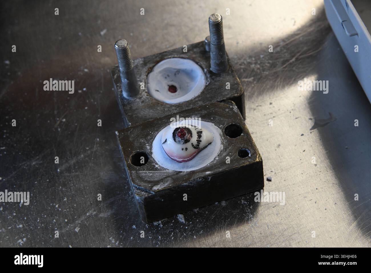 A custom-made prosthetic eye is placed in a two-part metal mold on a ...
