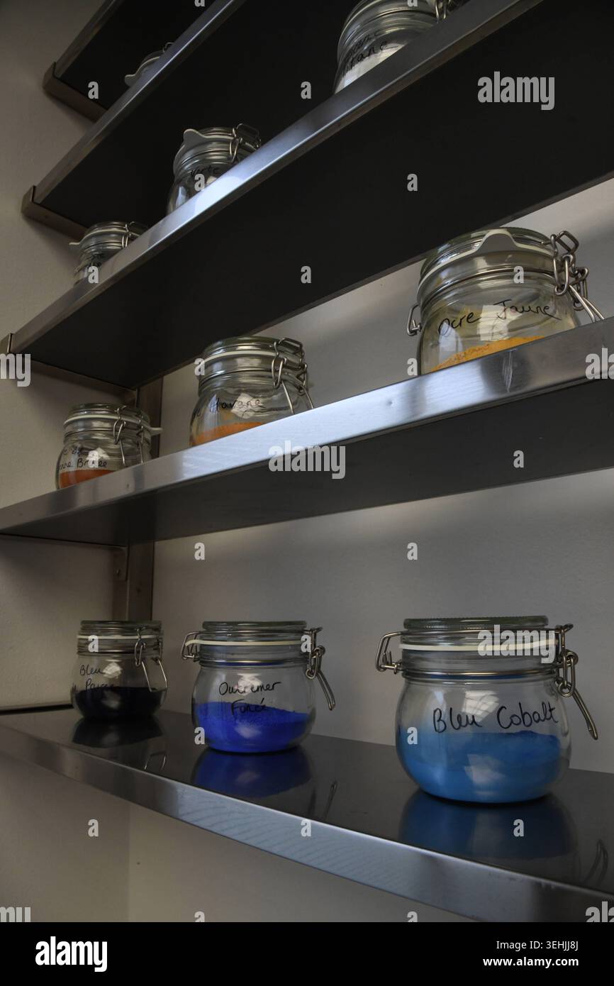 Glass jars containing powders of various colors are arranged on several ...