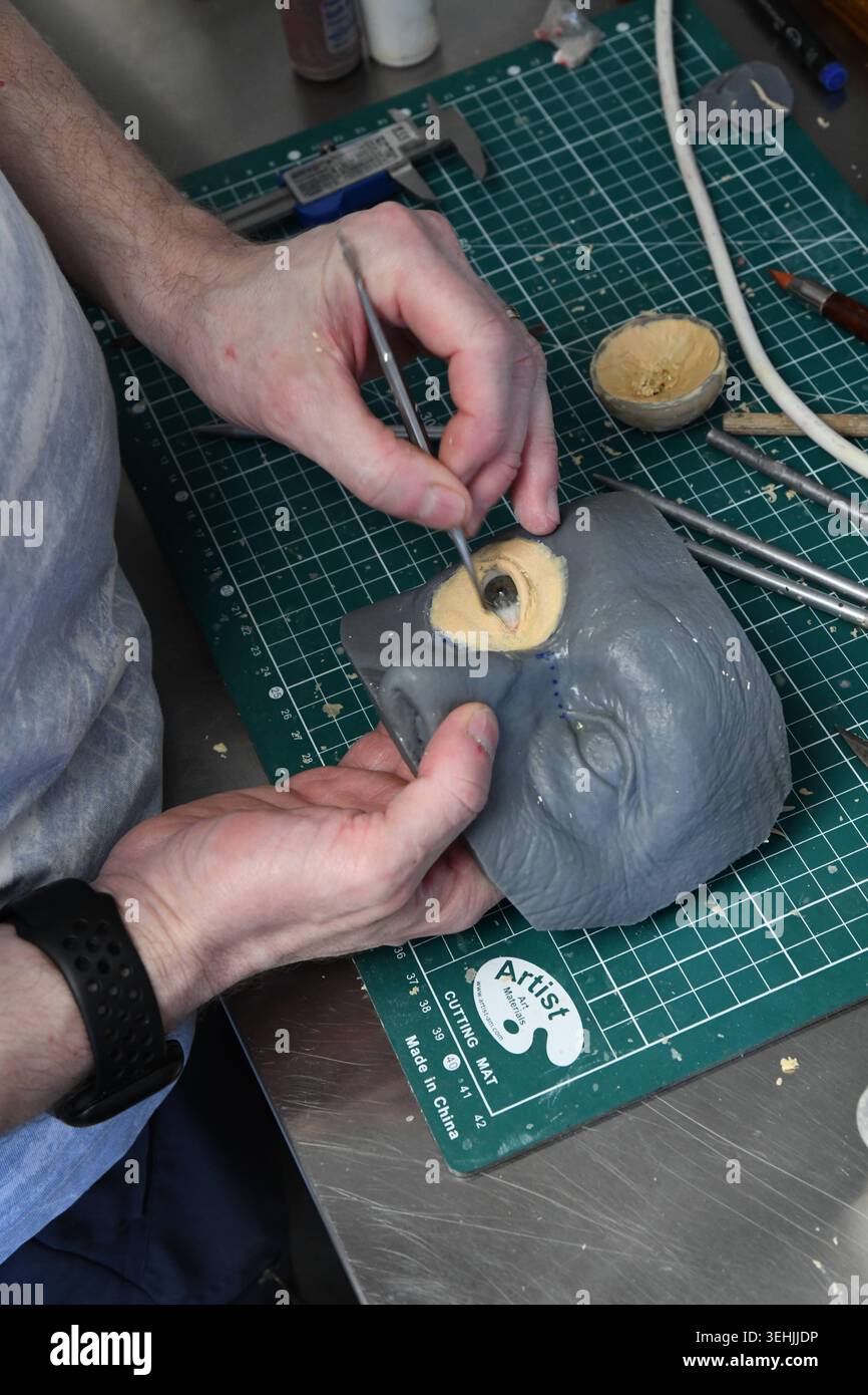 Ocularist using a metal tool to work on a small object inside a grey ...