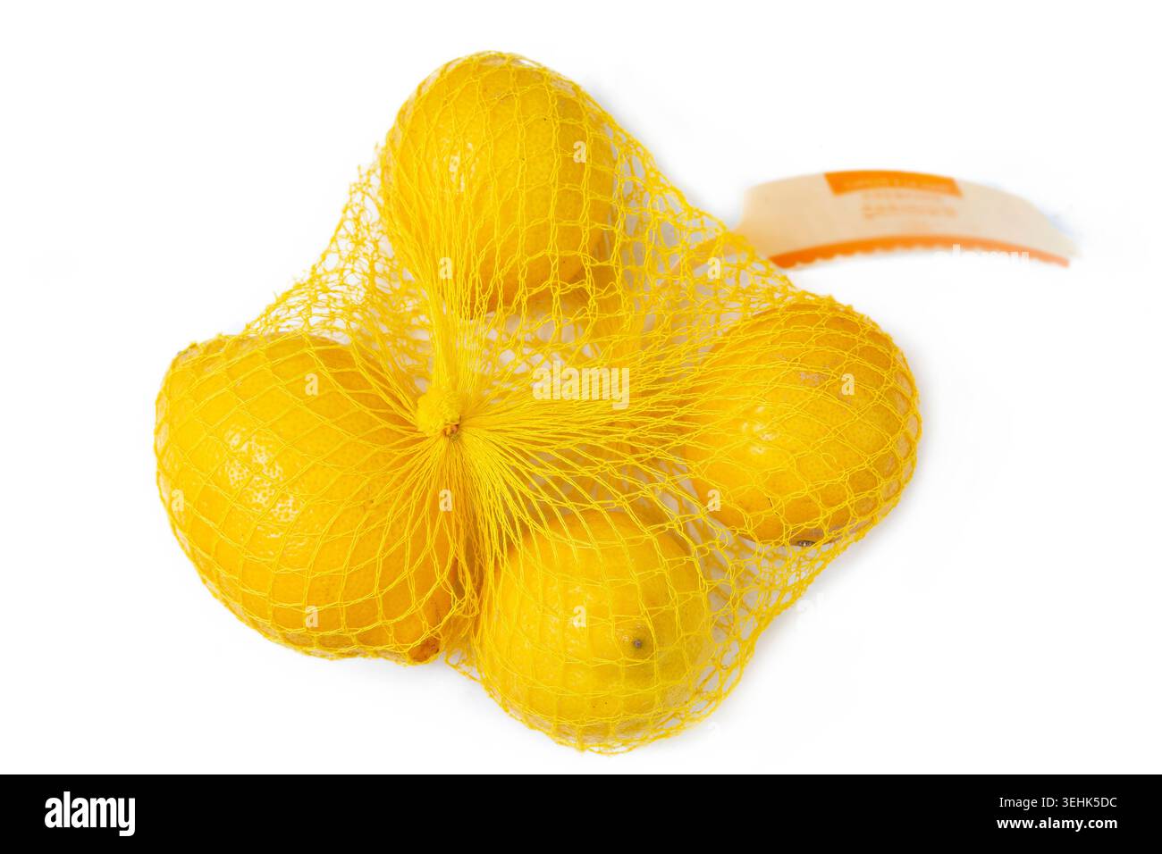 Four lemons are contained within a yellow plastic mesh bag on a white ...