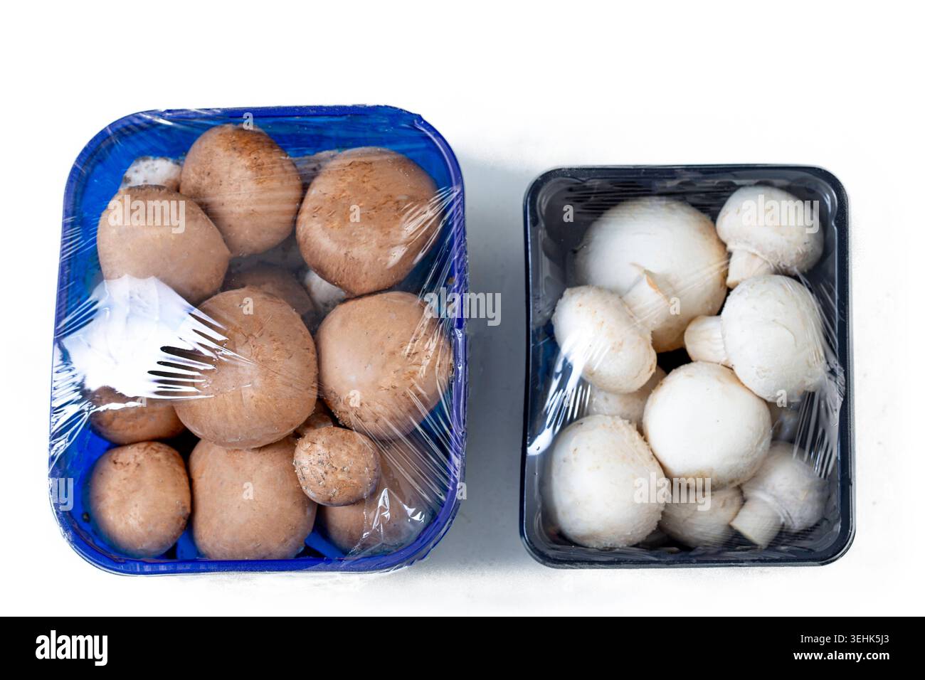 Two plastic containers wrapped in clear film hold mushrooms: brown ...