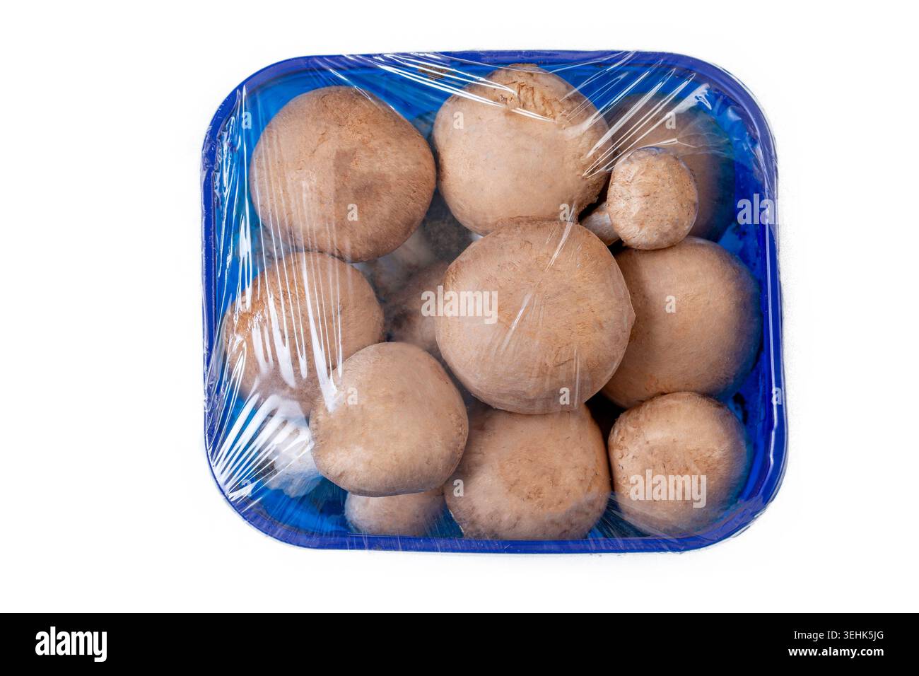 Brown mushrooms are contained in a blue plastic tray sealed with clear ...