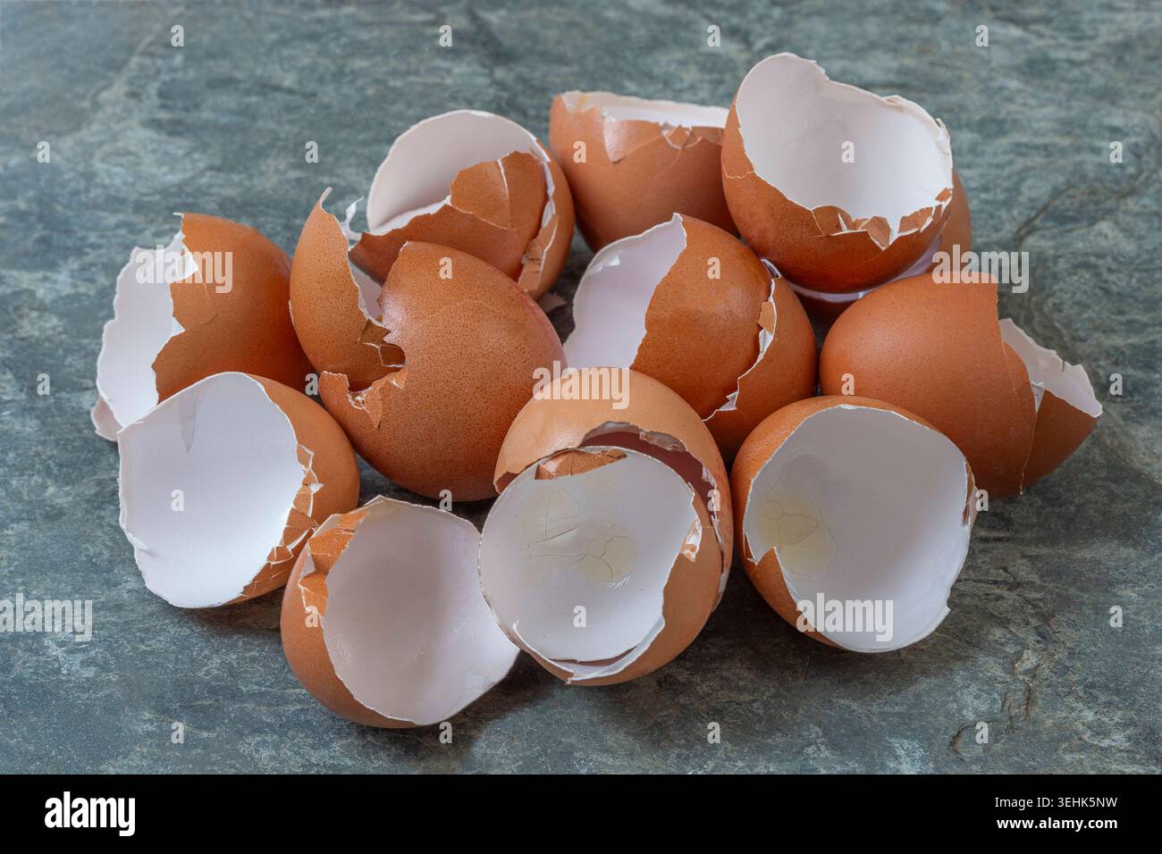A pile of broken brown eggshells sits on a grey stone surface. Broken ...