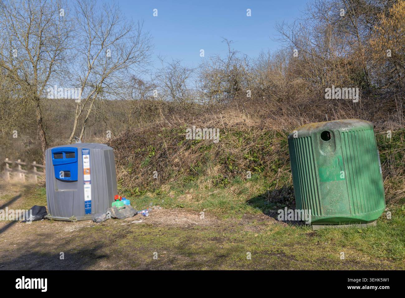 Two waste collection bins, one grey and one green, stand in a natural ...