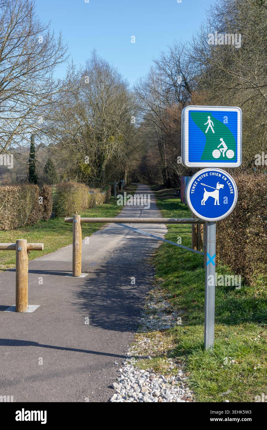 A paved path is blocked by wooden barriers. To the right, a post holds ...