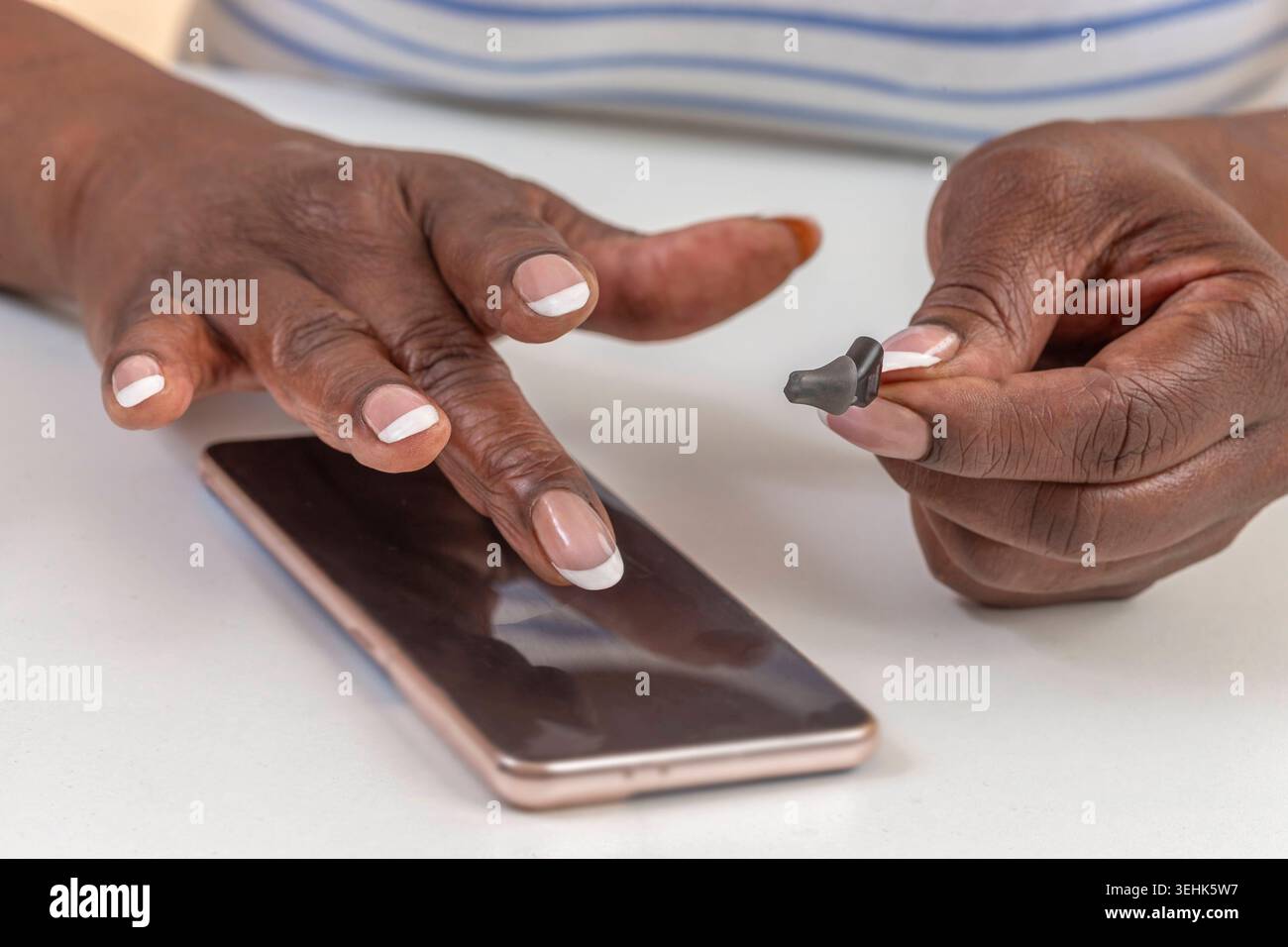 The hands of a person holding a small grey object and touching a ...