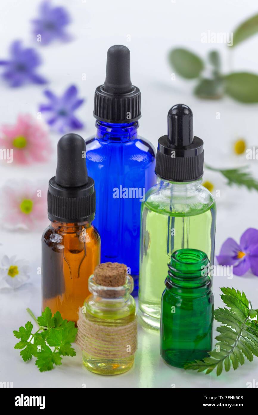 Five glass bottles of varying colors and sizes, some with droppers ...