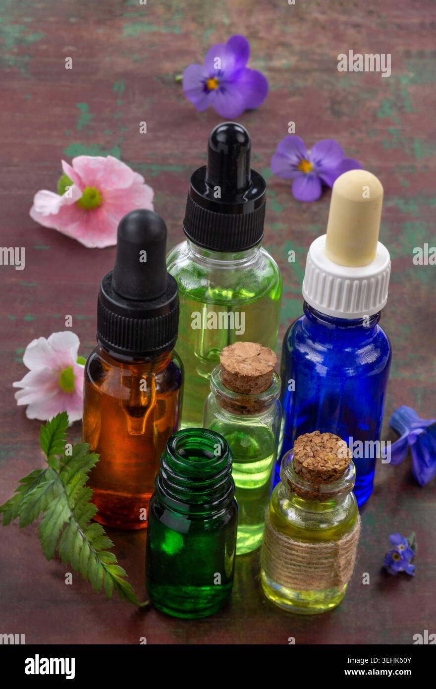 Six glass bottles containing liquids are surrounded by pansies Viola, a ...