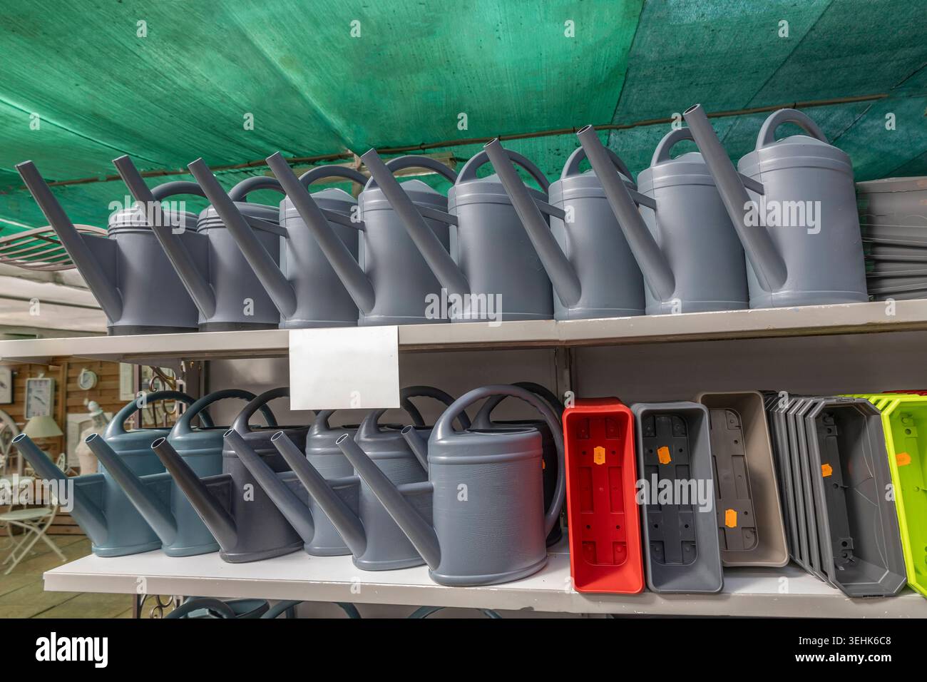 Grey plastic watering cans and colorful rectangular planting trays are ...