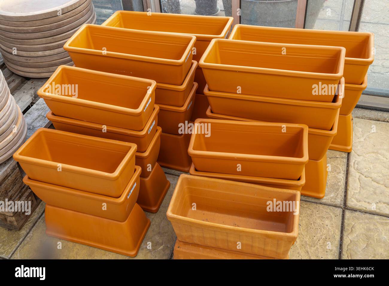 Stacks of rectangular orange plastic planters and circular grey pots ...