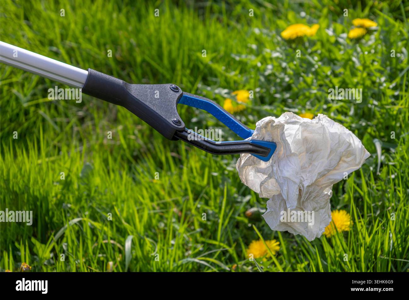 A litter picker tool with a metal handle and plastic grip holds a ...