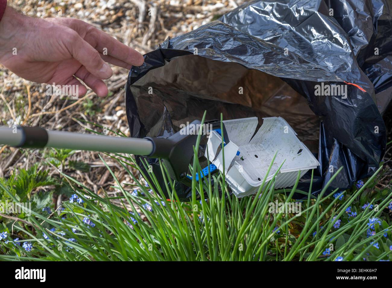 A person uses a litter picker tool to place a white polystyrene ...