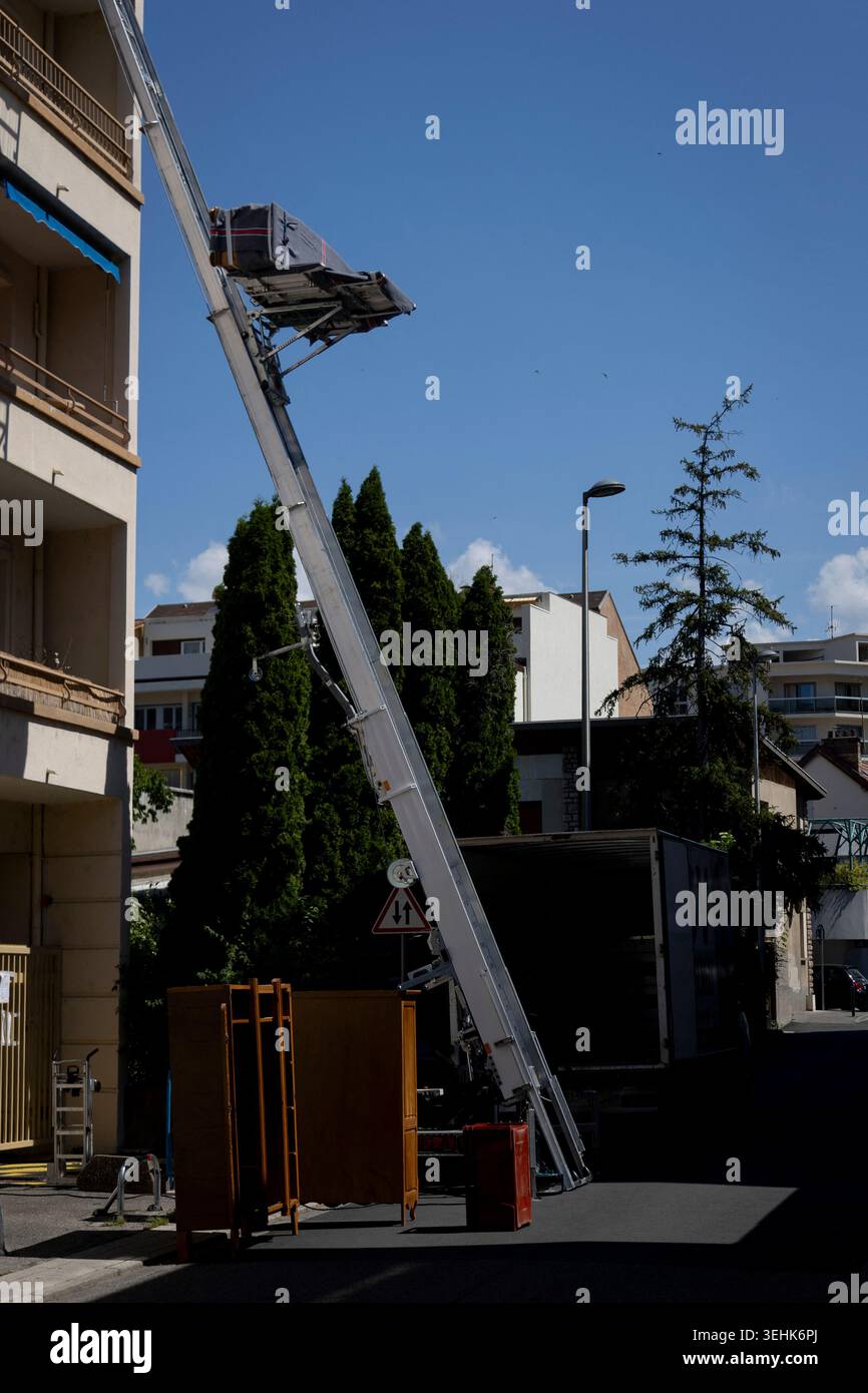 Movers use a furniture lift to lower a piece of furniture from an ...