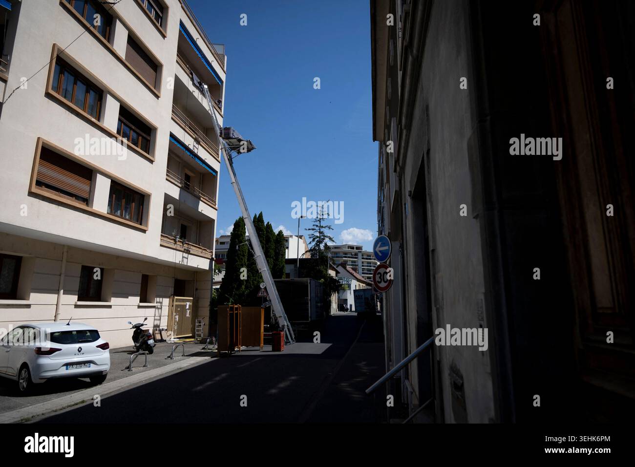 Movers use a furniture lift to lower a piece of furniture from an ...