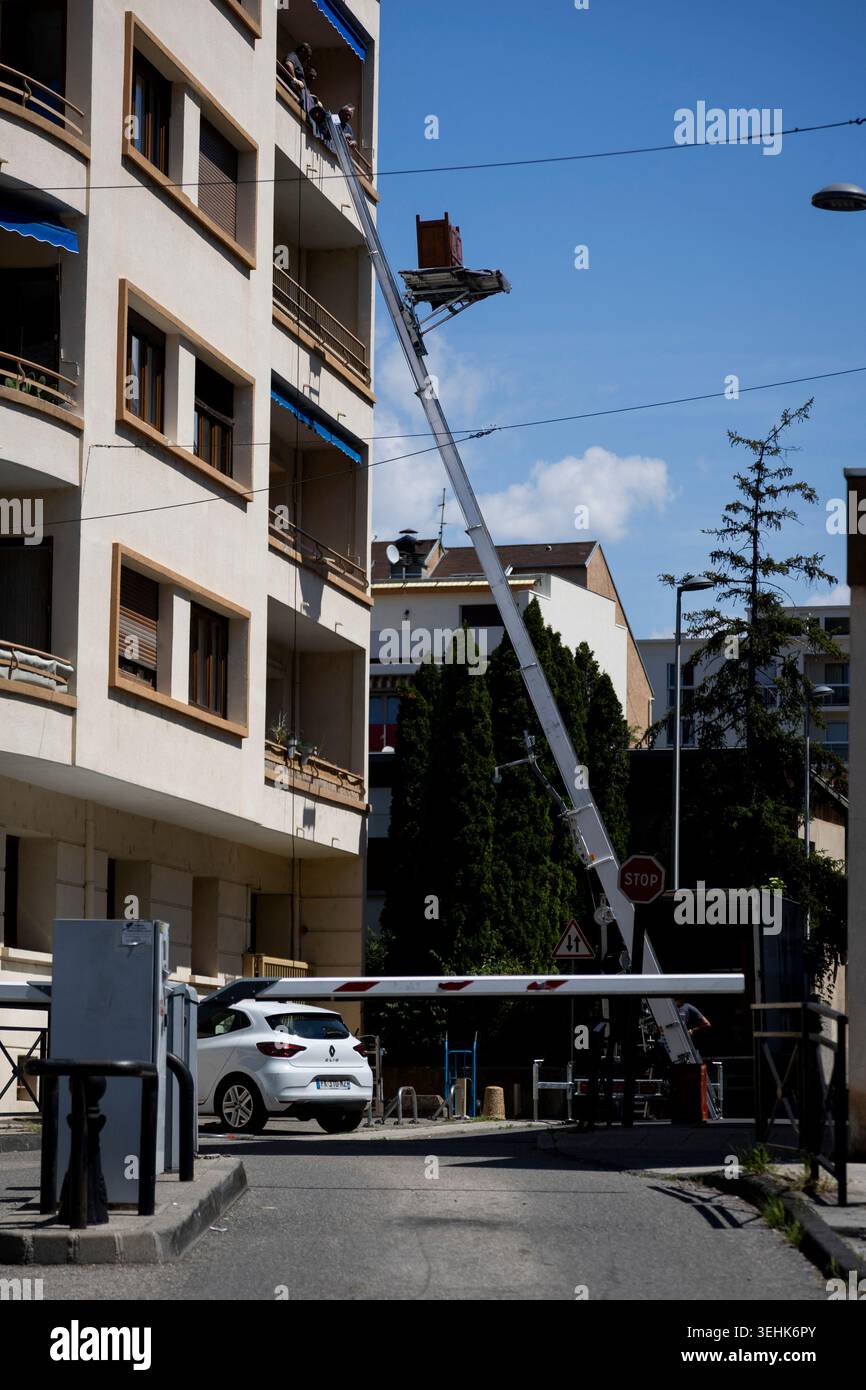 Movers use a furniture lift to lower a piece of furniture from an ...