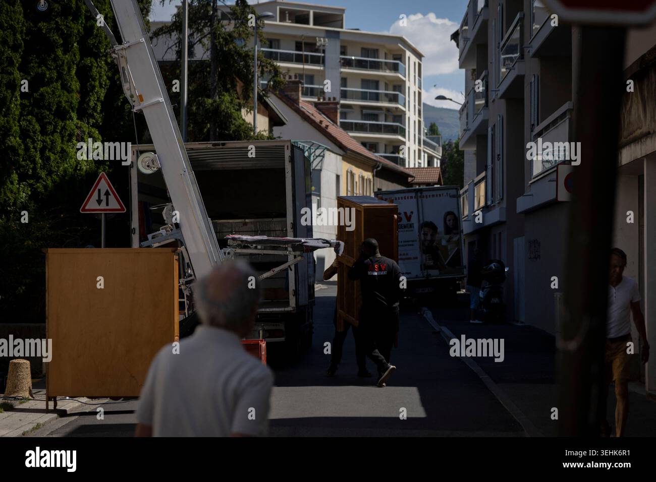 Movers use a furniture lift to lower a piece of furniture from an ...