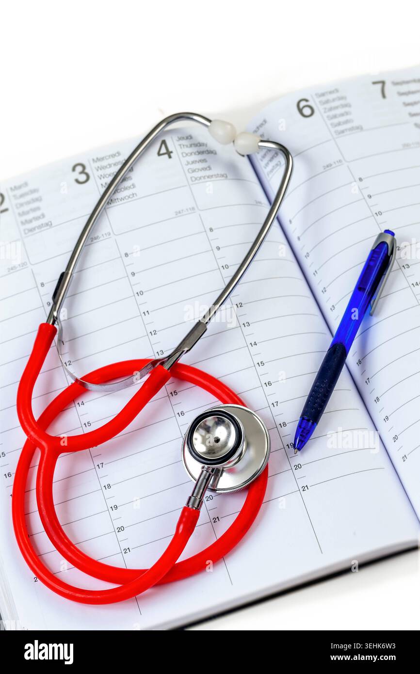 A red stethoscope and a blue pen are placed on an open calendar ...