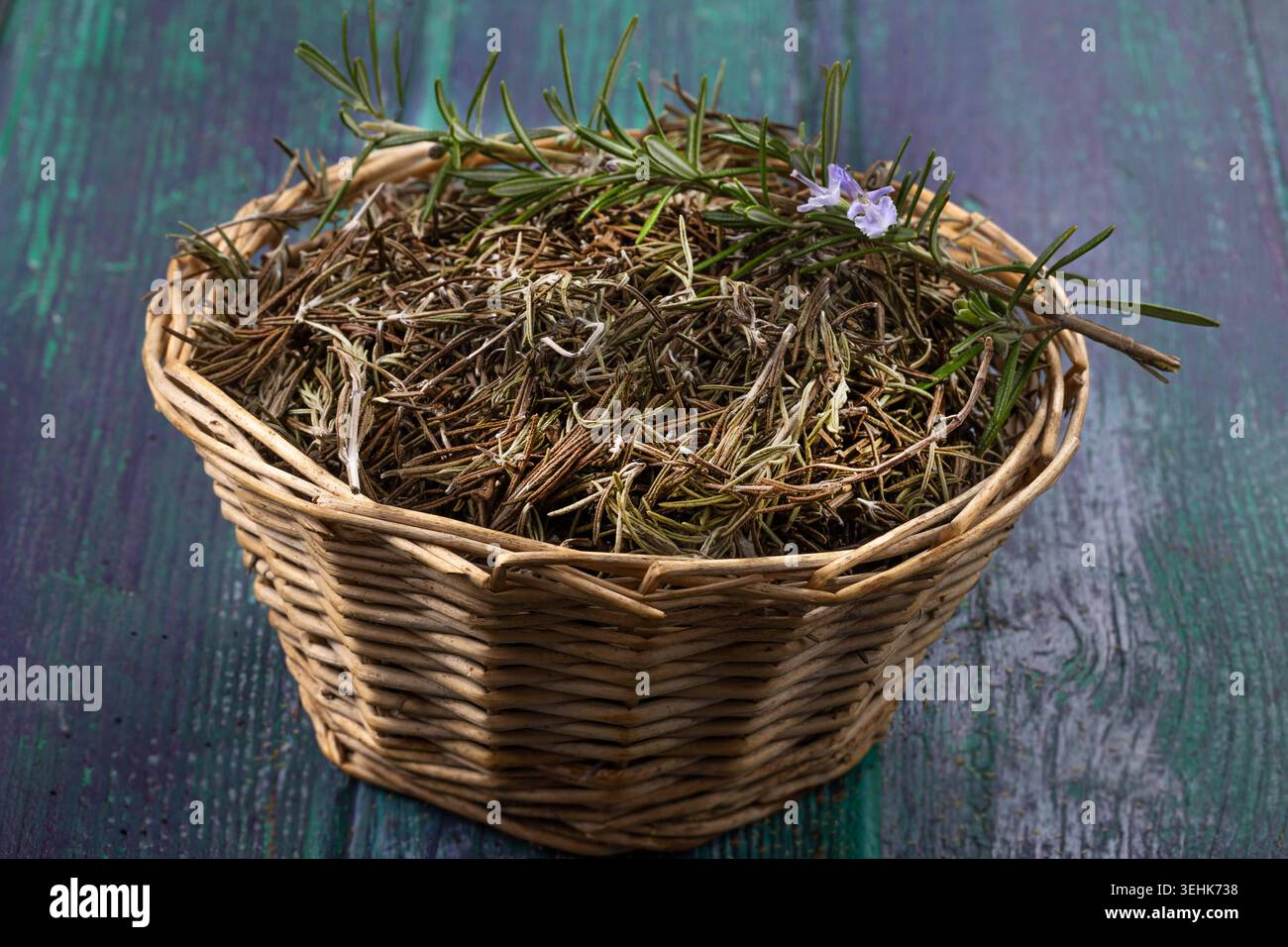 A wicker basket contains dried rosemary Salvia rosmarinus and a fresh ...