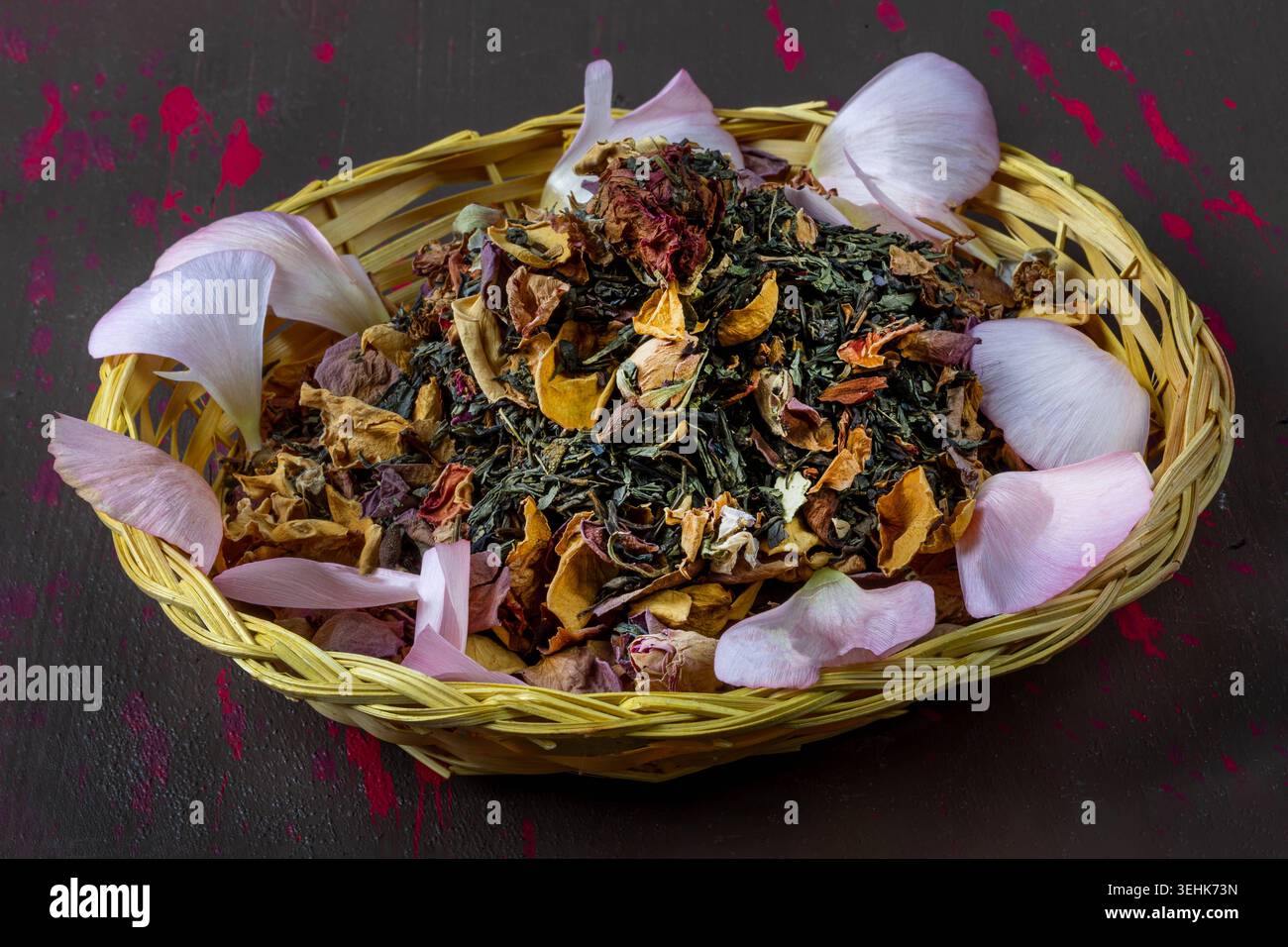 A yellow wicker basket contains dried tea leaves Camellia sinensis and ...