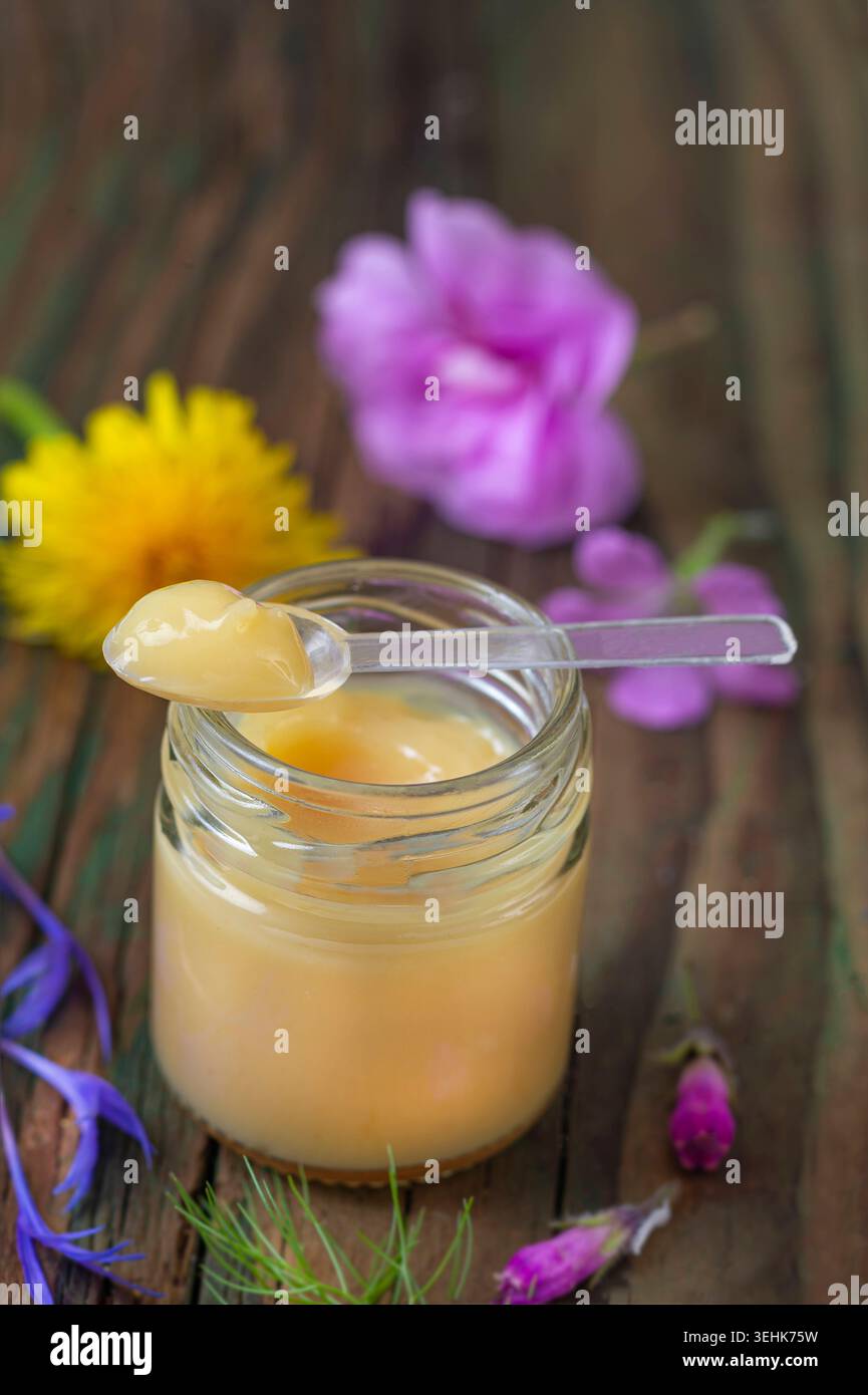 A glass jar contains honey. A transparent plastic spatula holds a ...