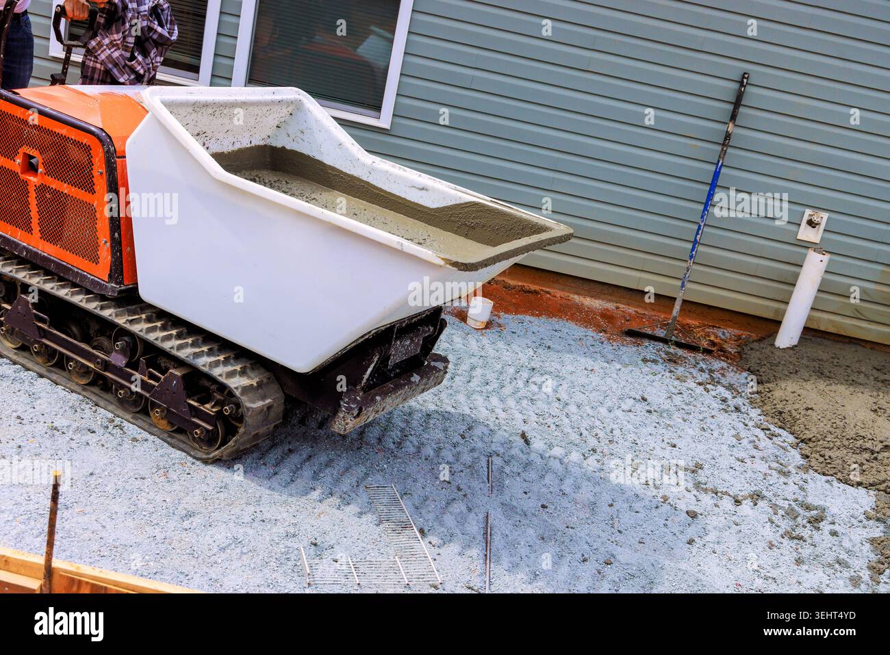 Concrete buggy is on construction site, moving wet cement across gravel ...