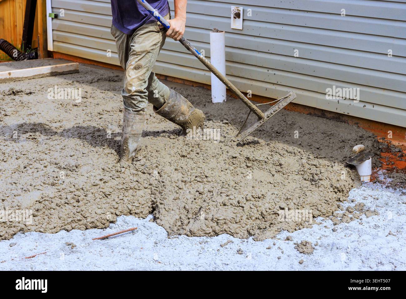 Worker uses level tool to smooth out wet concrete at home construction ...