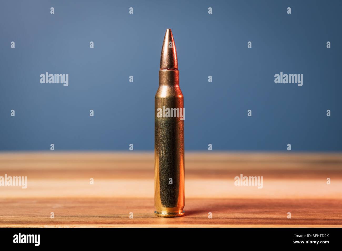 5.56x45mm rifle ammunition cartridge standing upright on a wooden ...