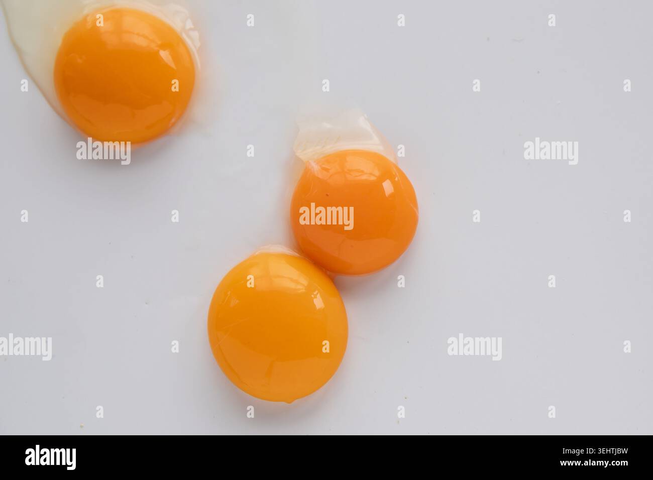 Three raw egg yolks with egg white on white background and fresh ...