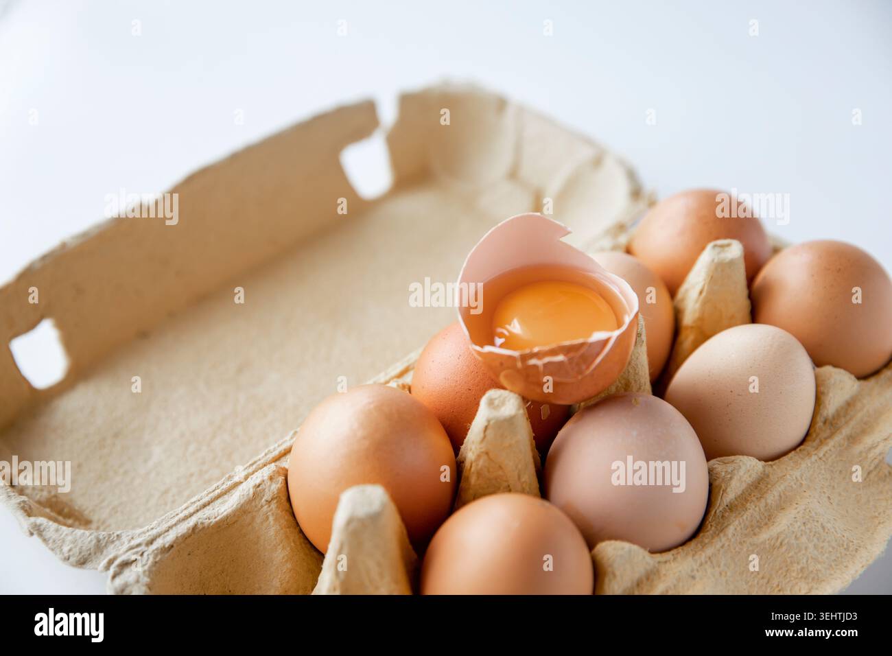 Raw egg yolk inside cracked eggshell in carton box with fresh chicken ...