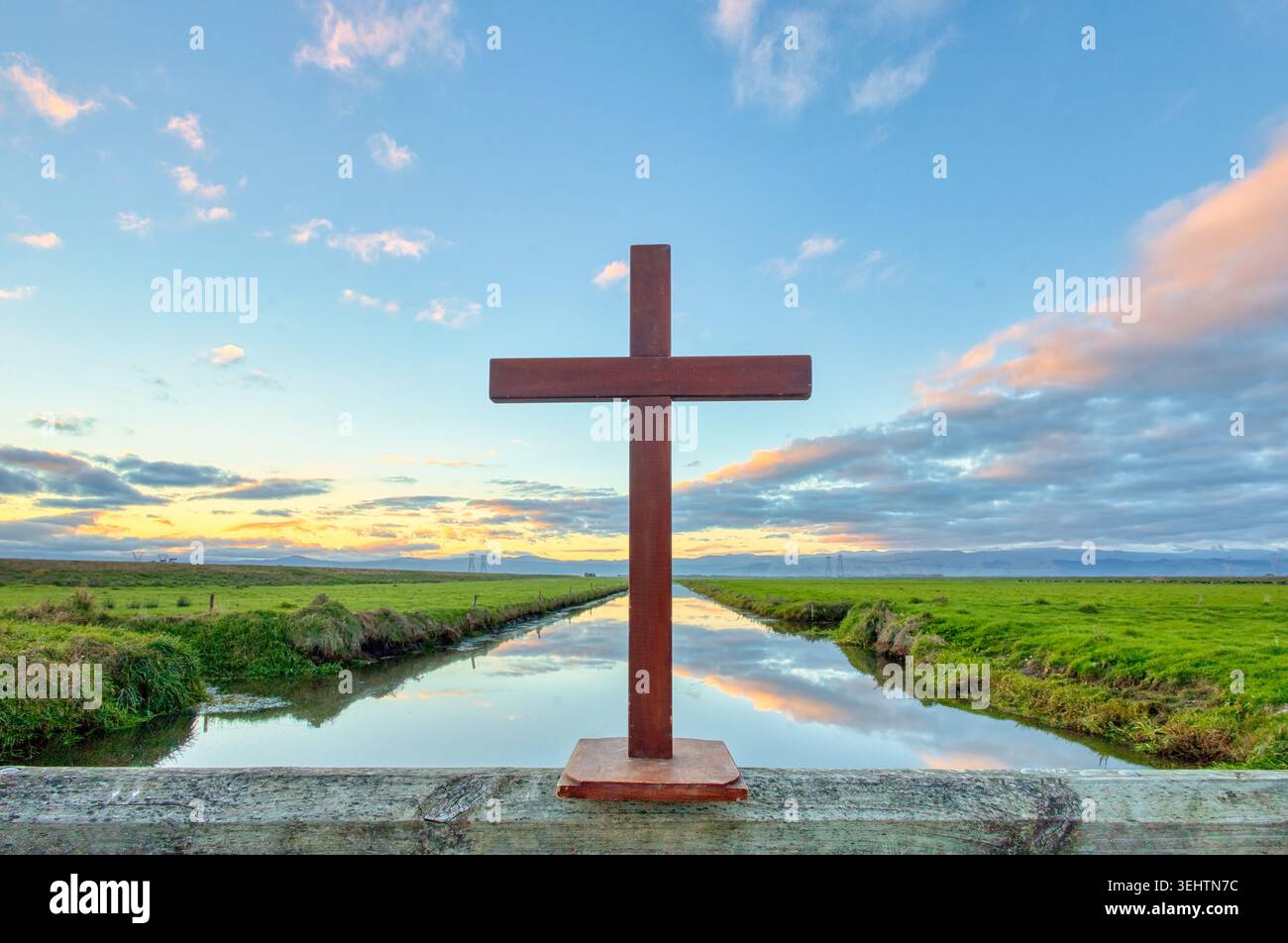 Wooden Cross at a water way with a wonderful sunrise sky in the ...