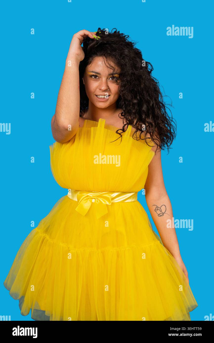 Young woman with curly hair expressing happiness against a blue ...