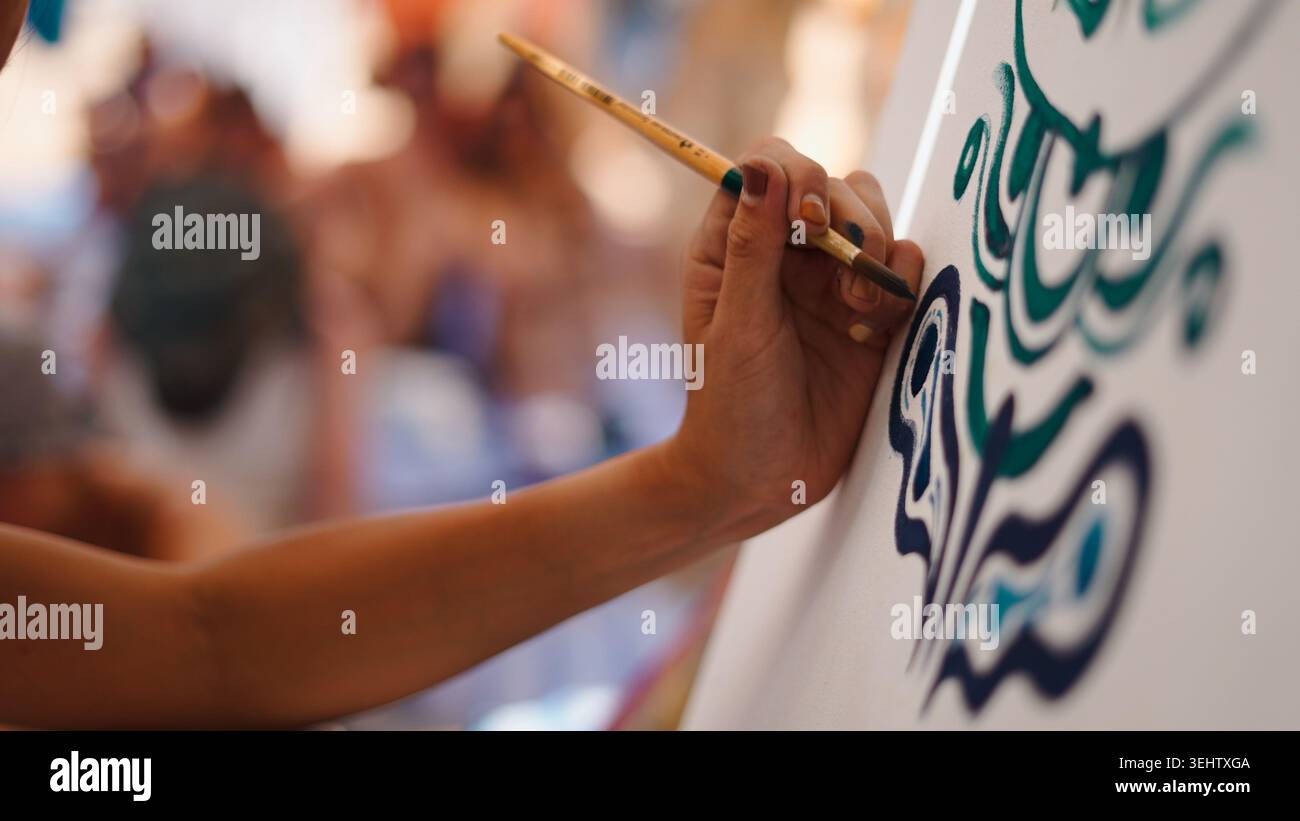 Artist's hand holding paintbrush painting calligraphy on canvas Stock ...