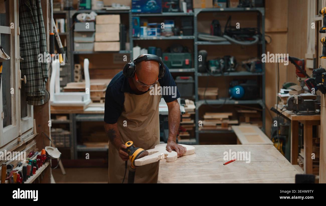 Wood artisan sanding guitar body, creating musical instrument in ...