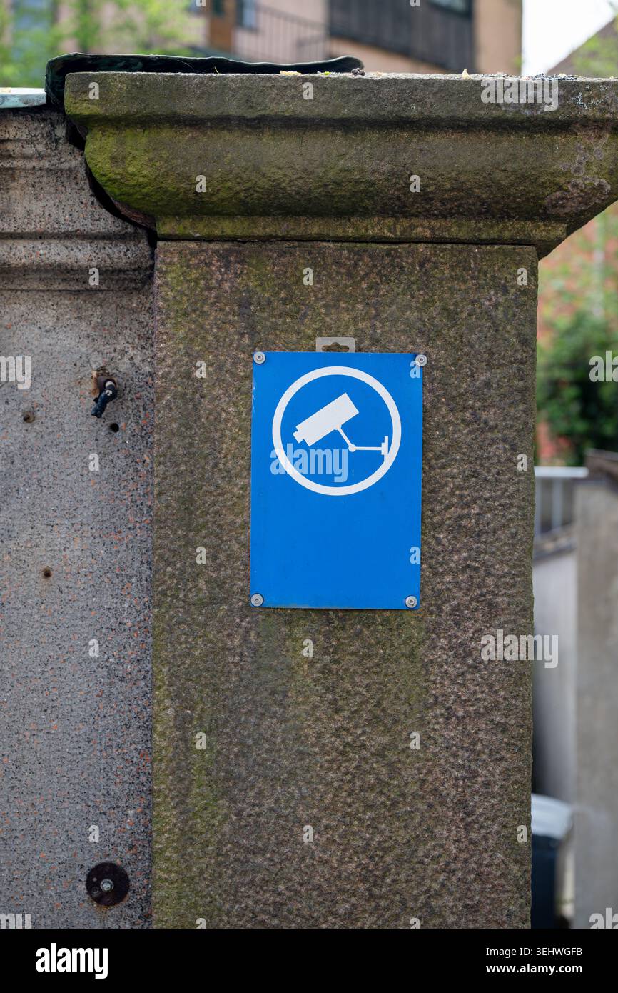 Blue surveillance camera security sign on stone wall in residential ...