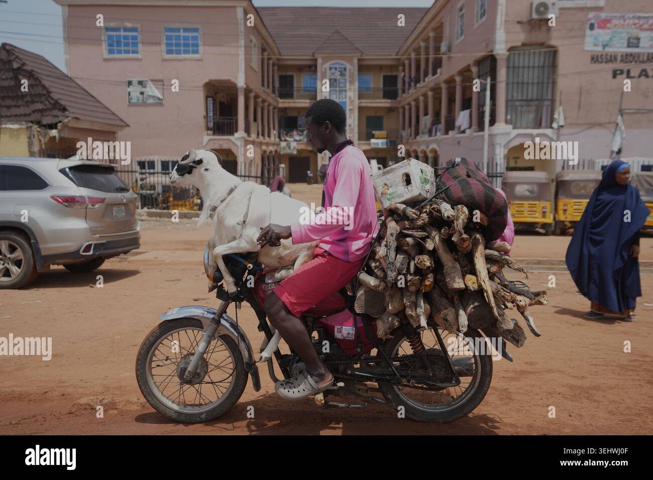 A motorbike taxi driver rides with a ram bought ahead of Eid Al-Adha ...