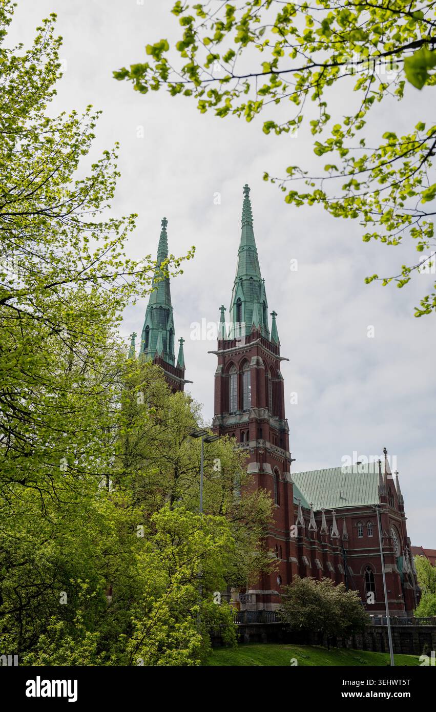 Spring view of red brick gothic church with twin spires framed by fresh ...