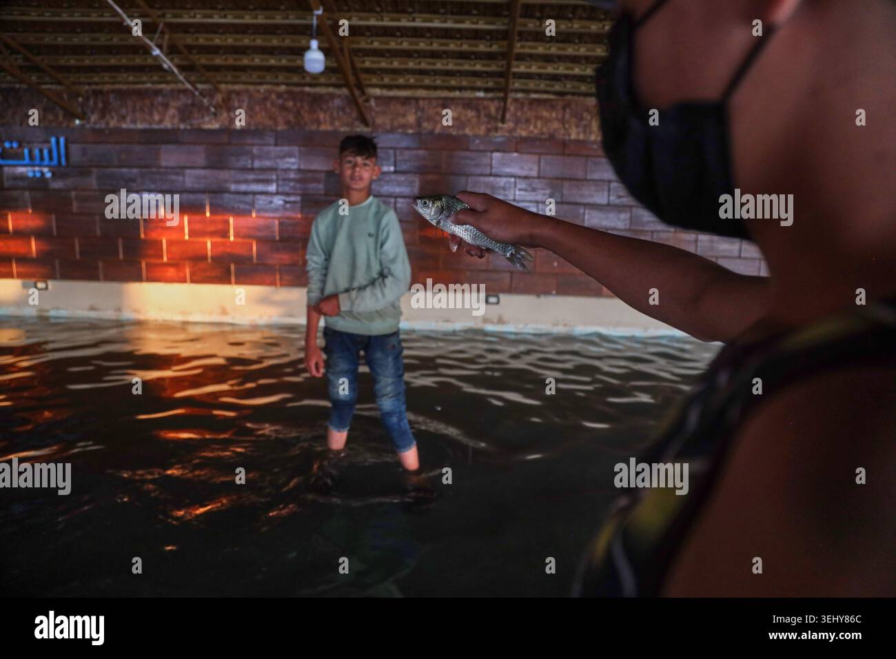 A man holds a fish caught while inspecting a flooded restaurant along ...