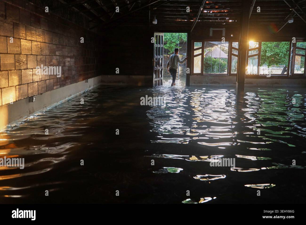 A man walks through a flooded restaurant along the banks of the ...