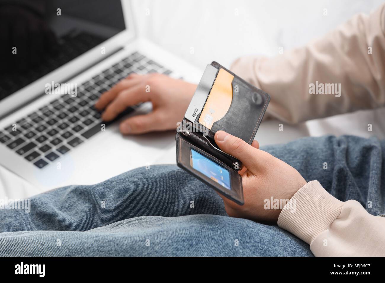 Man with wallet and credit cards using laptop in bedroom, closeup Stock ...
