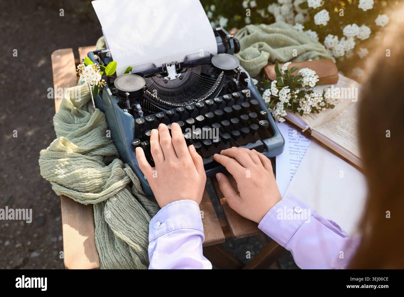 Woman using vintage typewriter in garden on spring day Stock Photo - Alamy