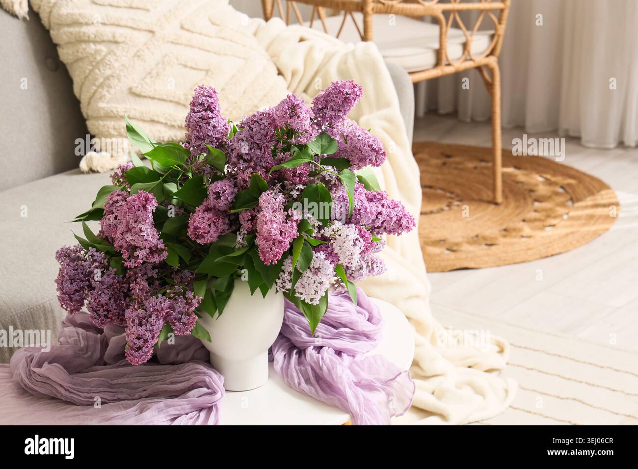 Vase with lilac flowers and cloth on table in living room Stock Photo ...